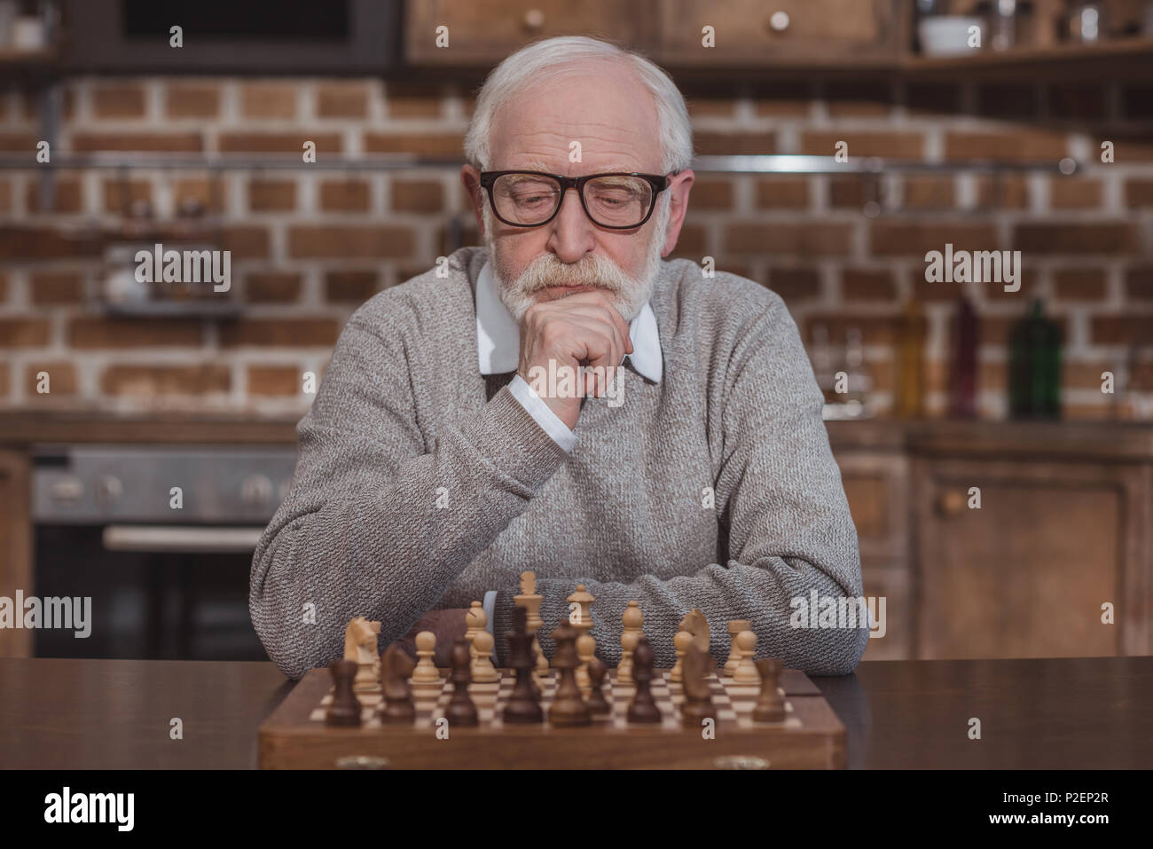 pensive handsome grey hair man thinking and looking at chessboard at ...