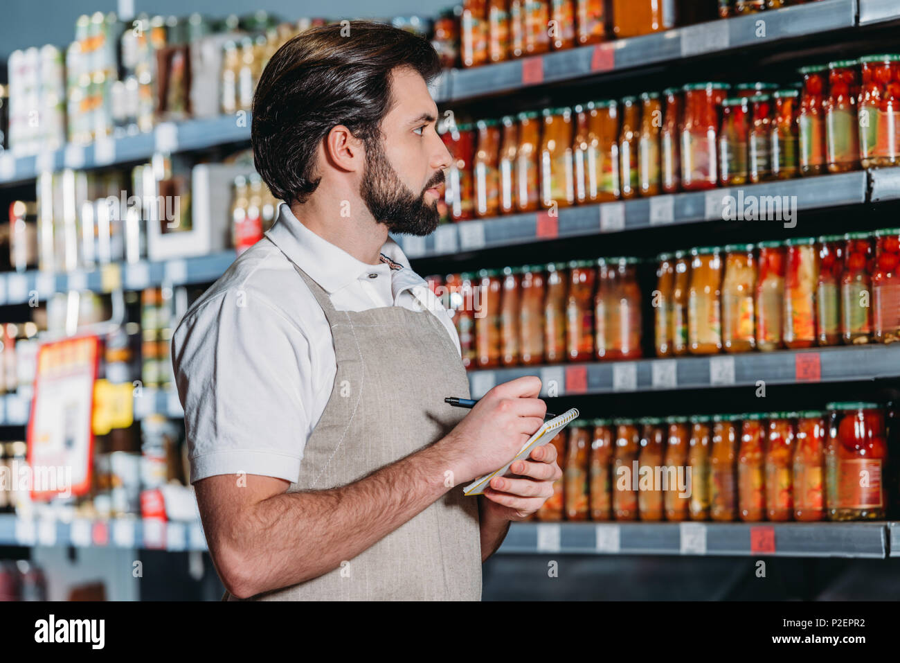side view of shop assistant in apron with notebook in supermarket Stock ...
