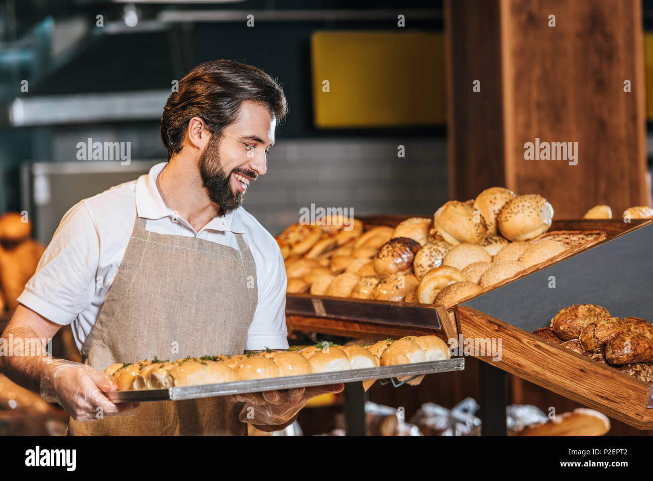 smiling male shop assistant arranging fresh pastry in supermarket Stock ...