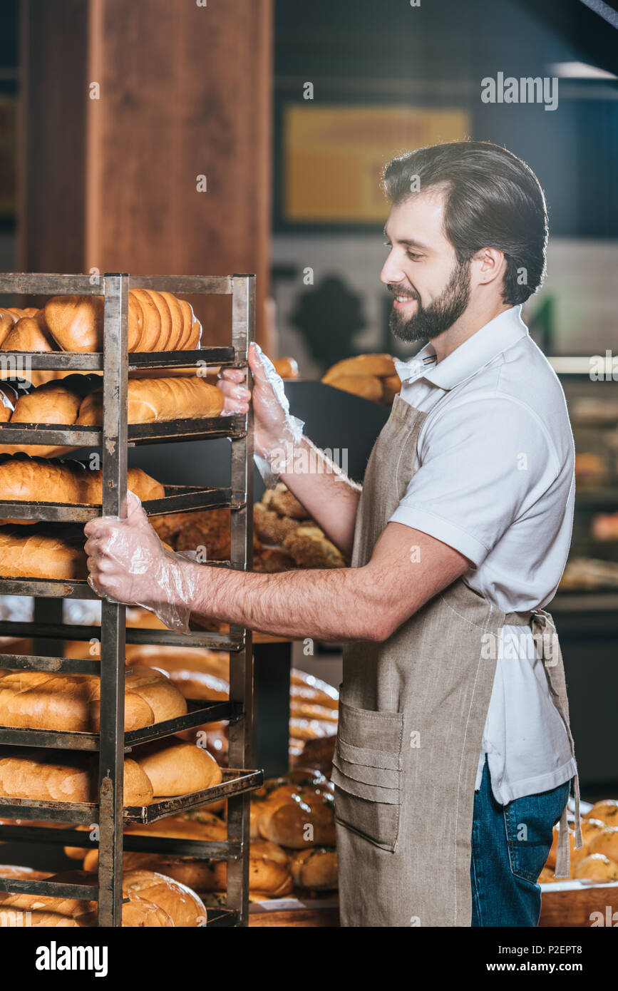 smiling male shop assistant arranging fresh pastry in supermarket Stock ...