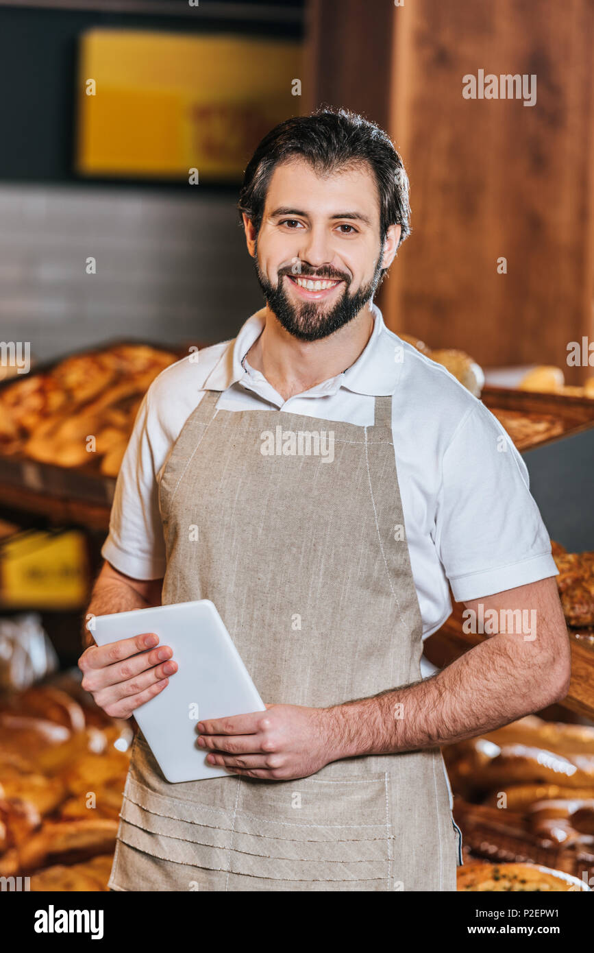 portrait of smiling shop assistant with tablet looking at camera in ...
