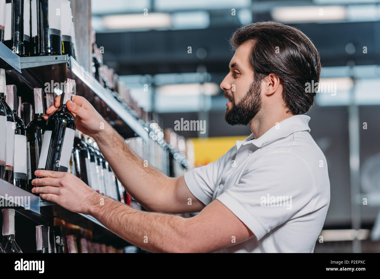 male shop assistant arranging alcohol in supermarket Stock Photo - Alamy