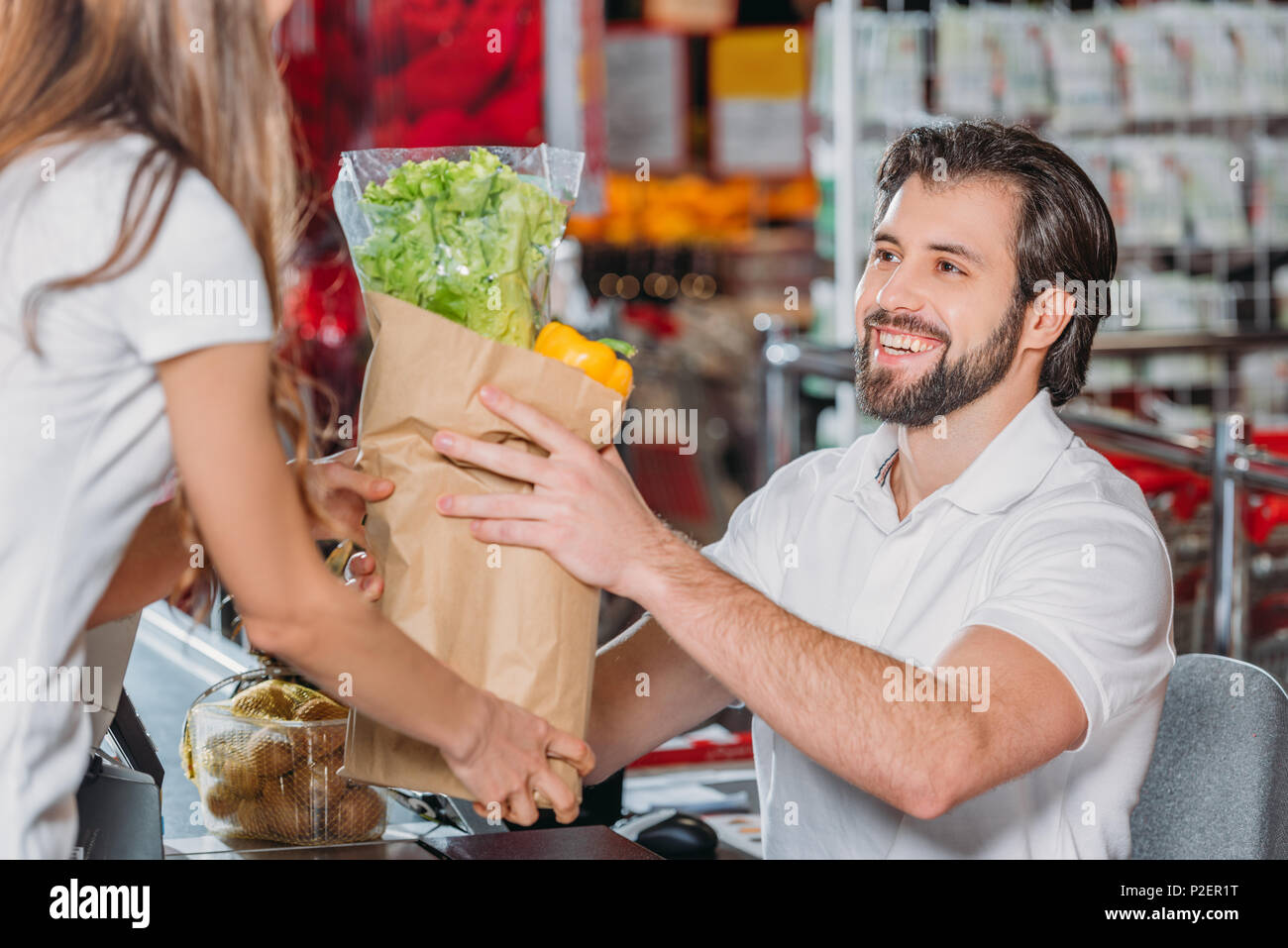 smiling shop assistant giving purchase to shopper in supermarket Stock ...