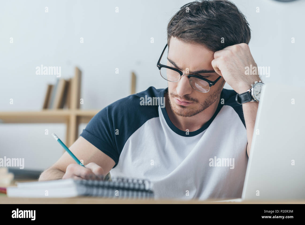 handsome male student in eyeglasses writing in copybook Stock Photo - Alamy