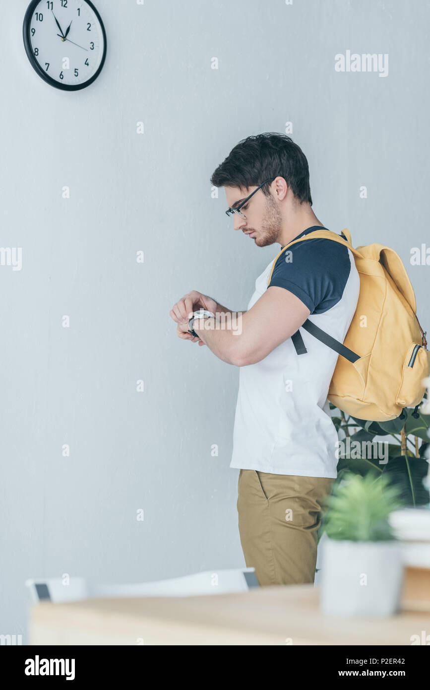 handsome male student with backpack looking at wristwatch Stock Photo ...