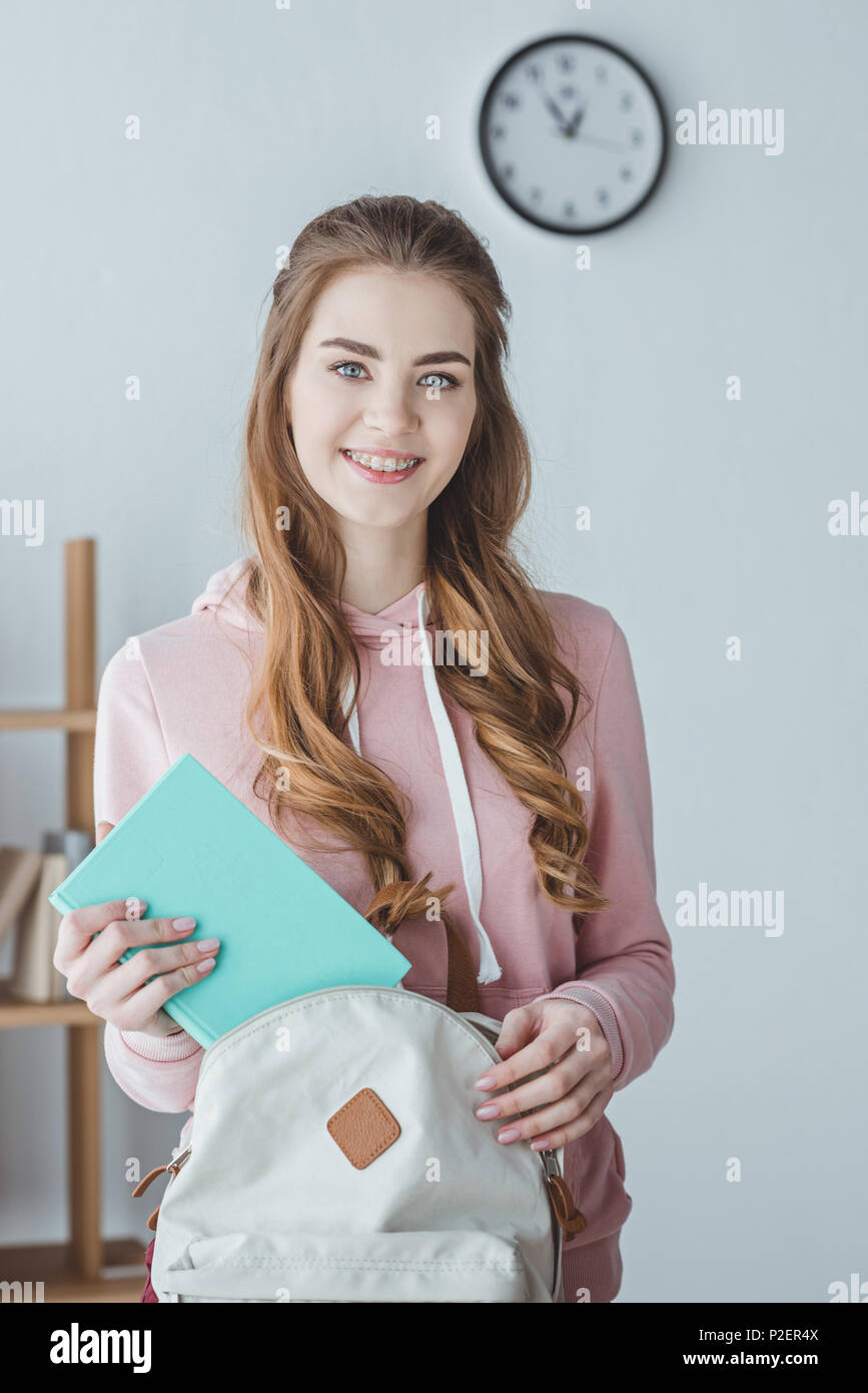 attractive female student putting book into backpack Stock Photo - Alamy