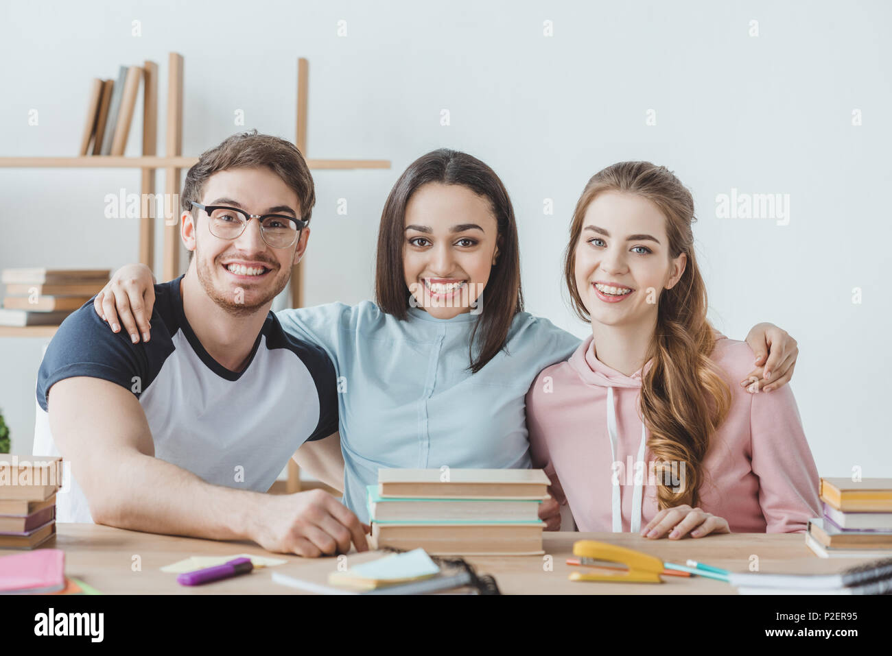 young smiling students sitting at table with books Stock Photo - Alamy