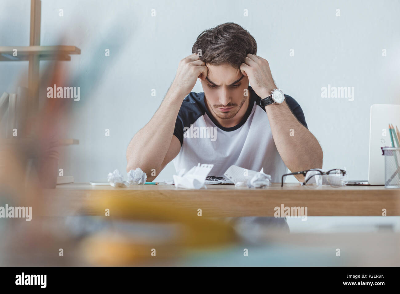 tired student studying at table with crumpled papers Stock Photo - Alamy