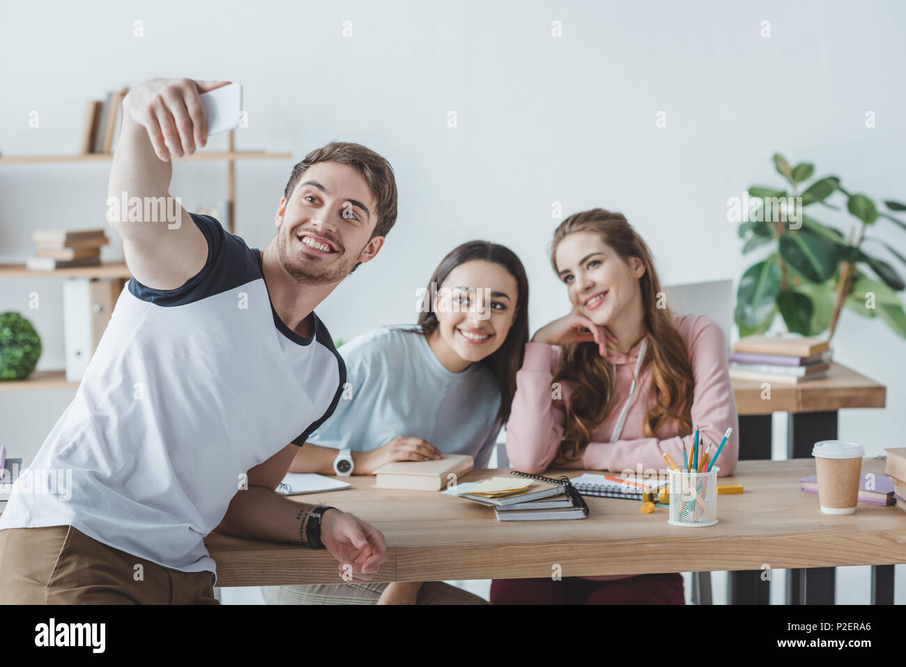 multiethnic students taking selfie on smartphone while studying ...