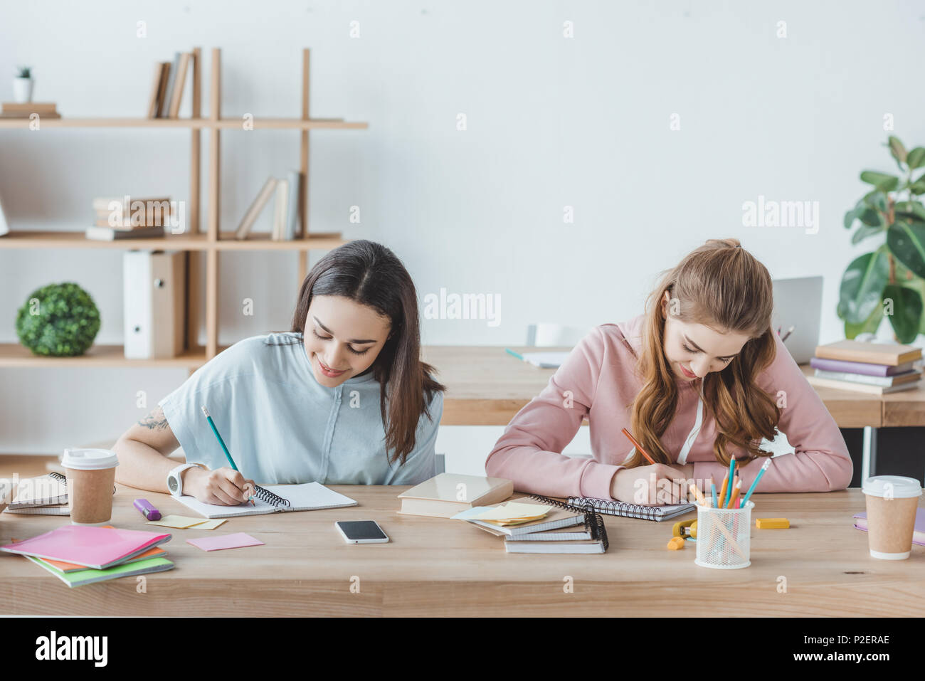 female multiethnic students writing examination together Stock Photo ...