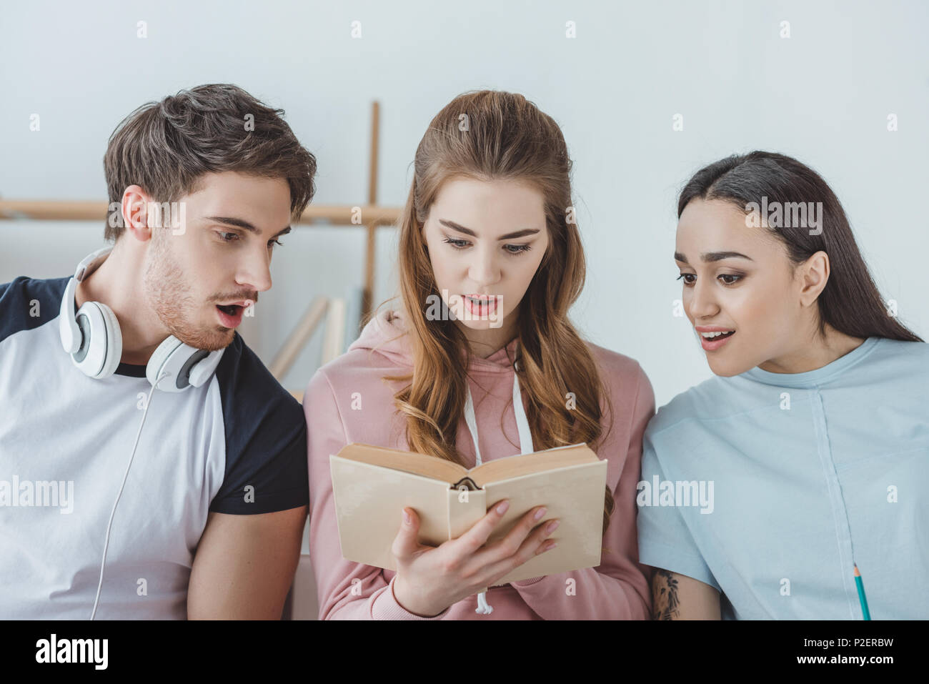 shocked young students reading one book Stock Photo - Alamy