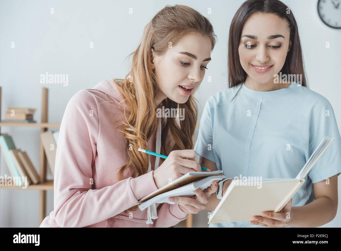 multicultural girls writing something while studying with book Stock ...