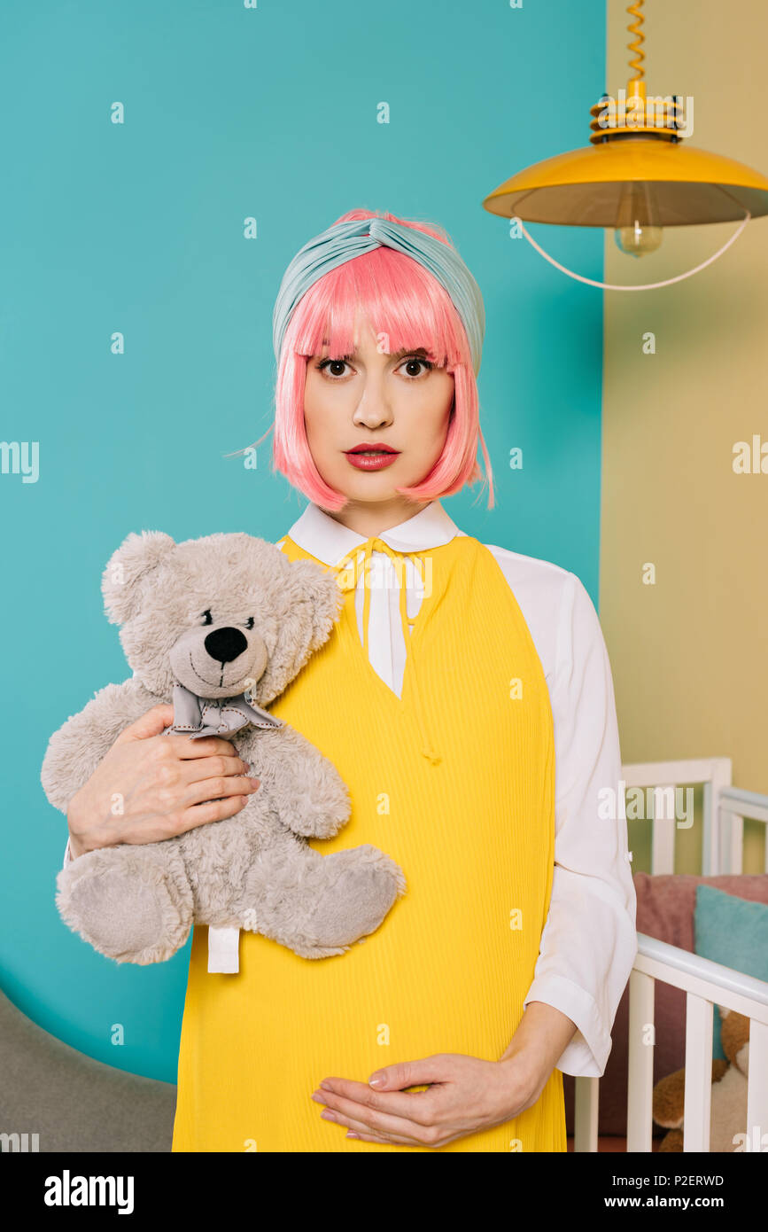 portrait of retro styled pregnant pin up woman with pink hair holding ...