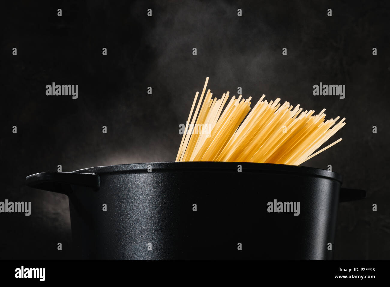 spaghetti boiling in black pan on dark background Stock Photo - Alamy