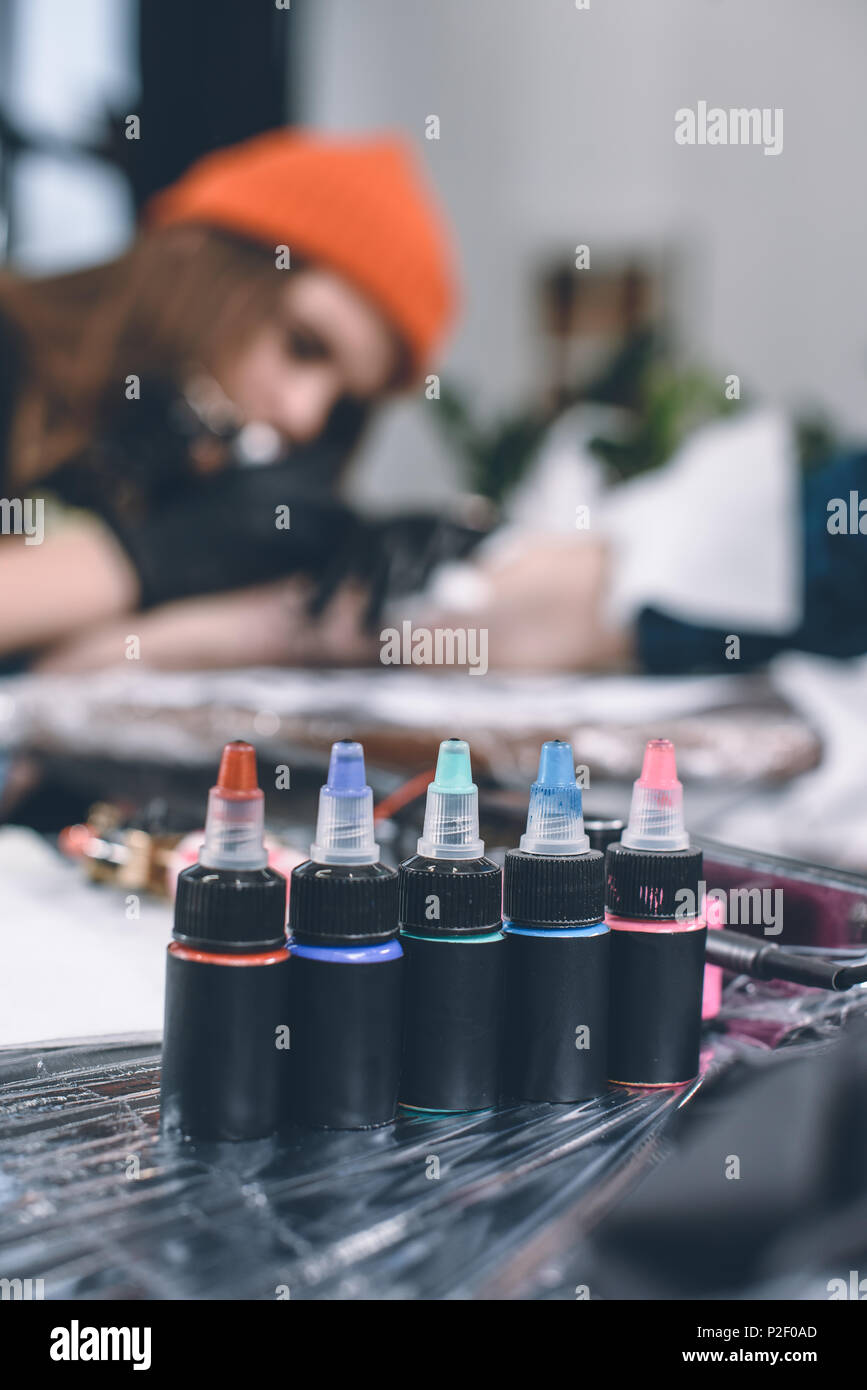 Bottles of ink in front of working tattoo master Stock Photo - Alamy