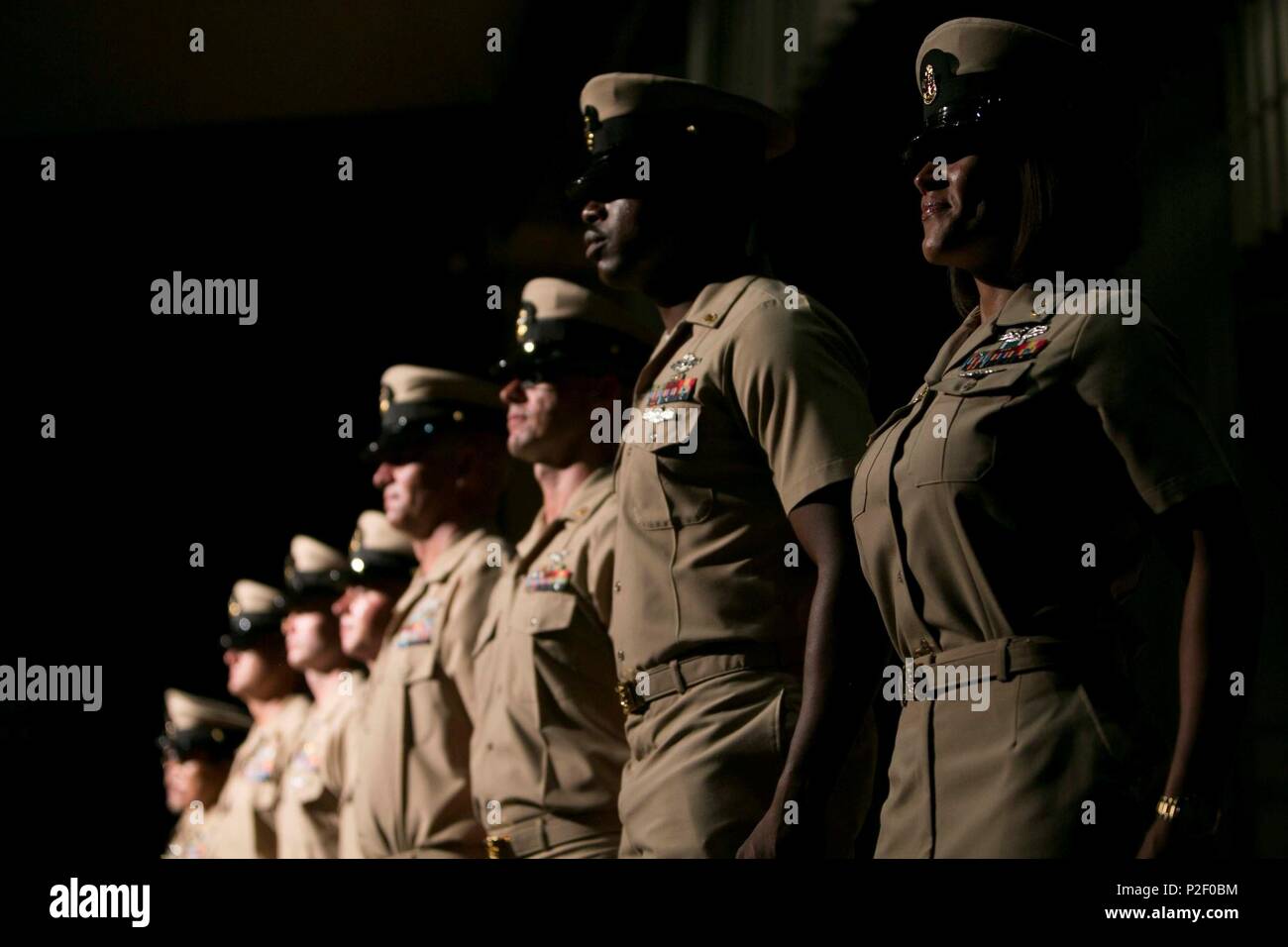 Newly promoted Chief Petty Officers stand at the position of attention ...