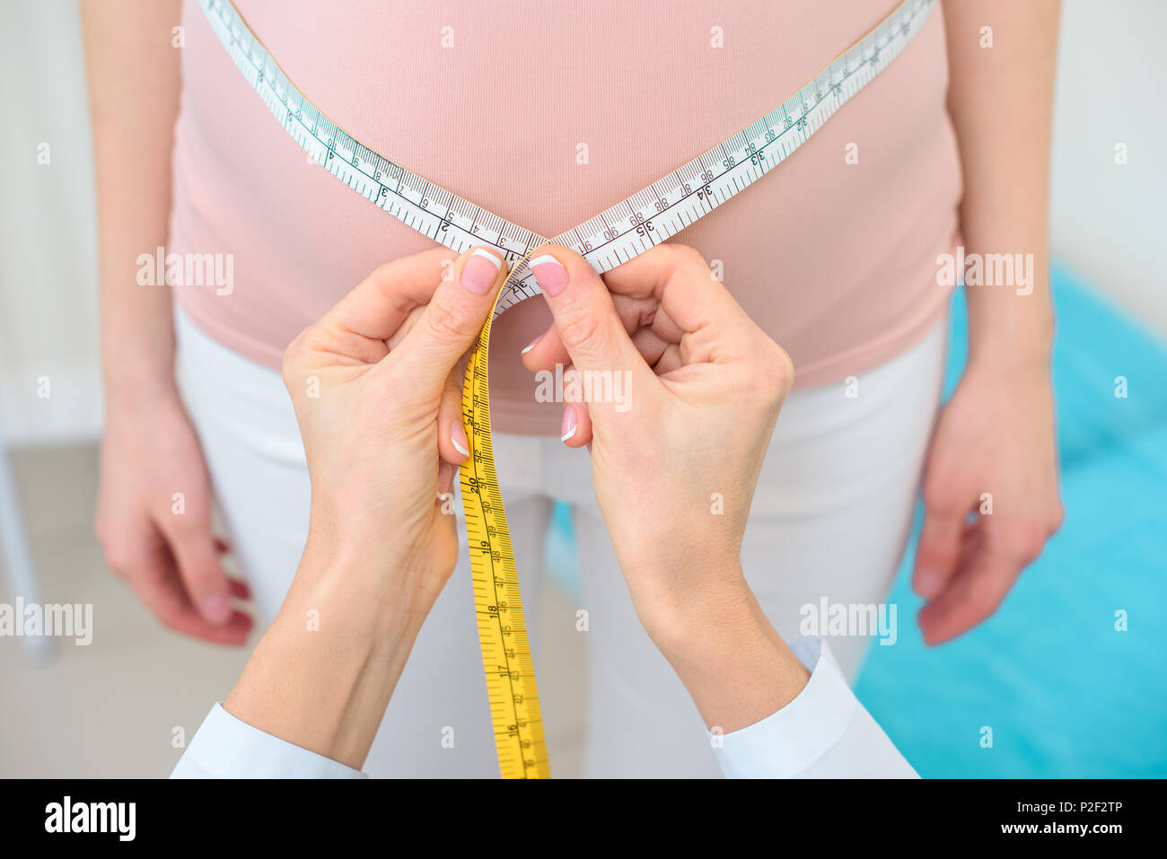 cropped shot of female obstetrician gynecologist measuring belly size ...