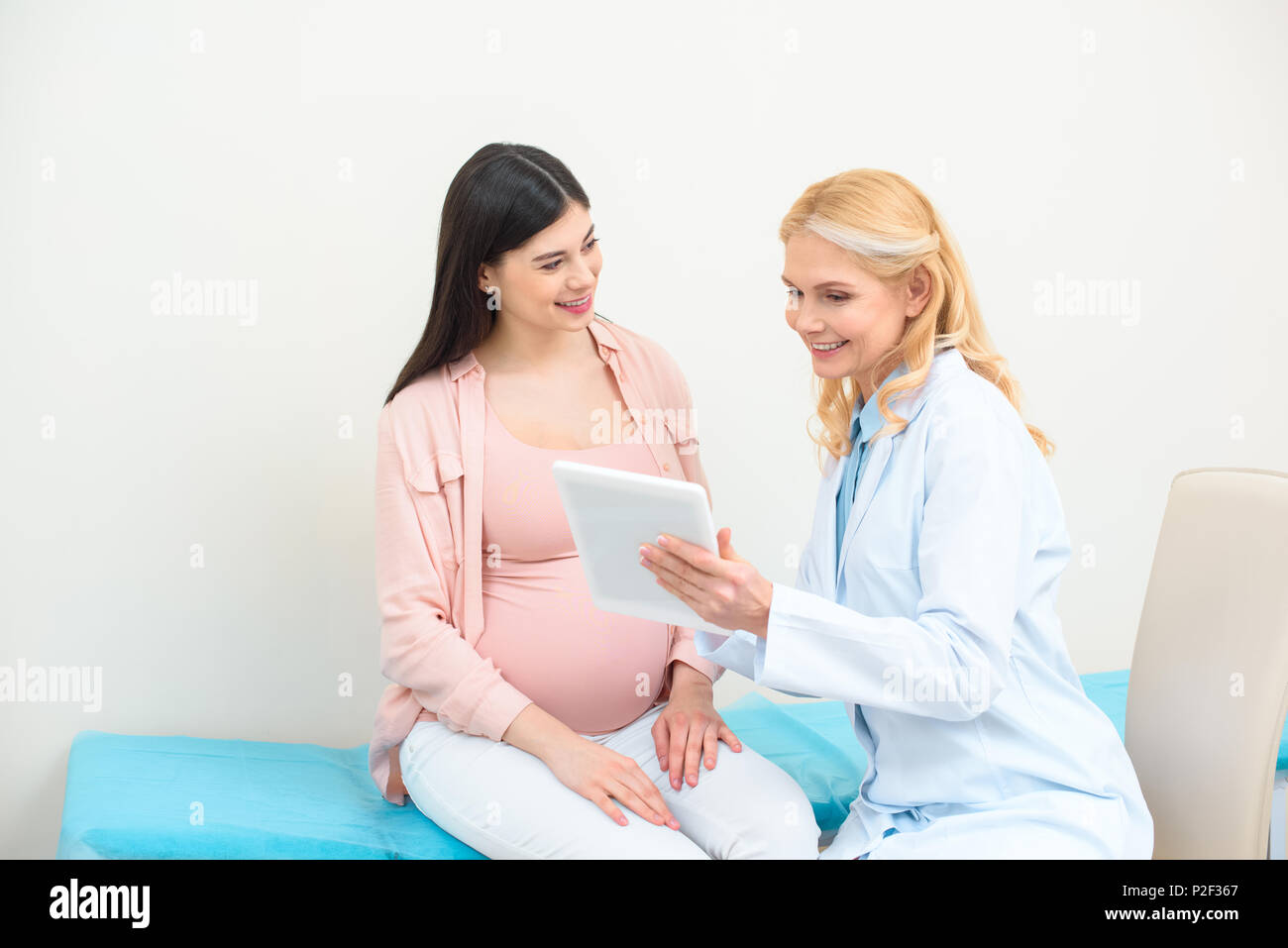 obstetrician gynecologist and pregnant woman using tablet together ...