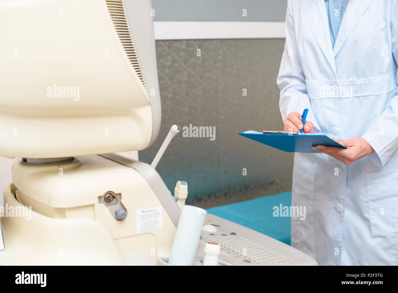 obstetrician gynecologist in front of ultrasonic scanner writing in ...