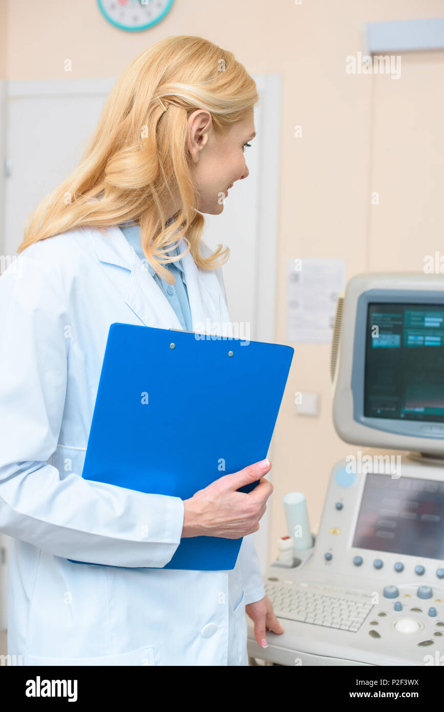 obstetrician gynecologist with clipboard looking at ultrasonic scanner ...