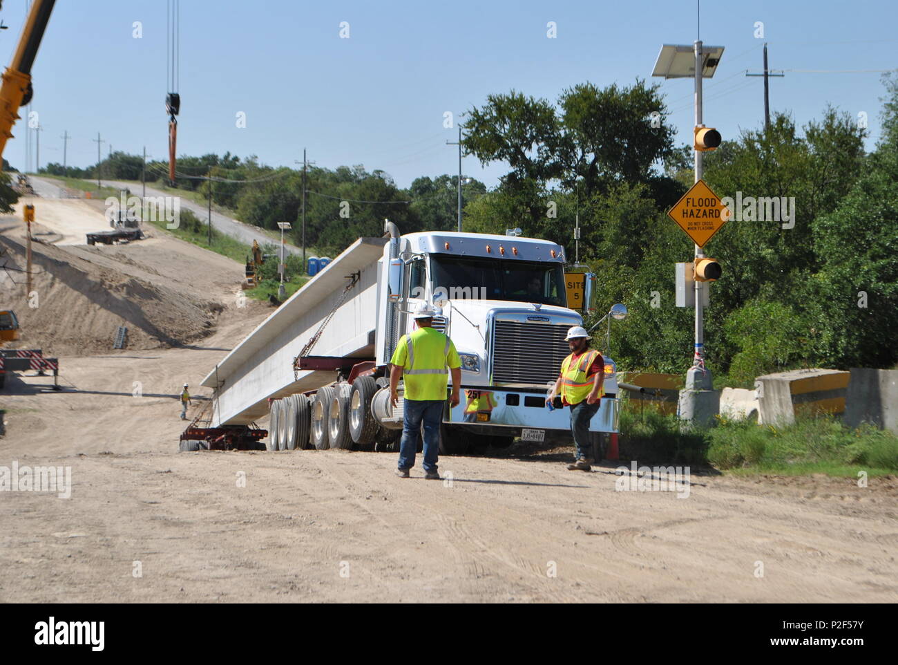 The 18-wheeler driver slowly backs the beam down a slope and into ...