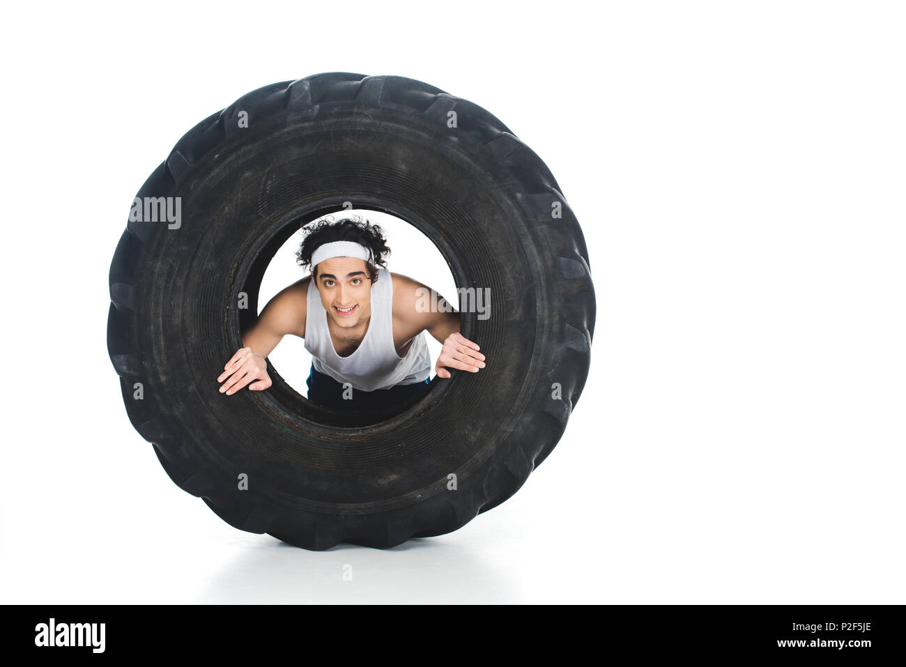 Thin sportsman with headband inside tire of wheel isolated on white ...