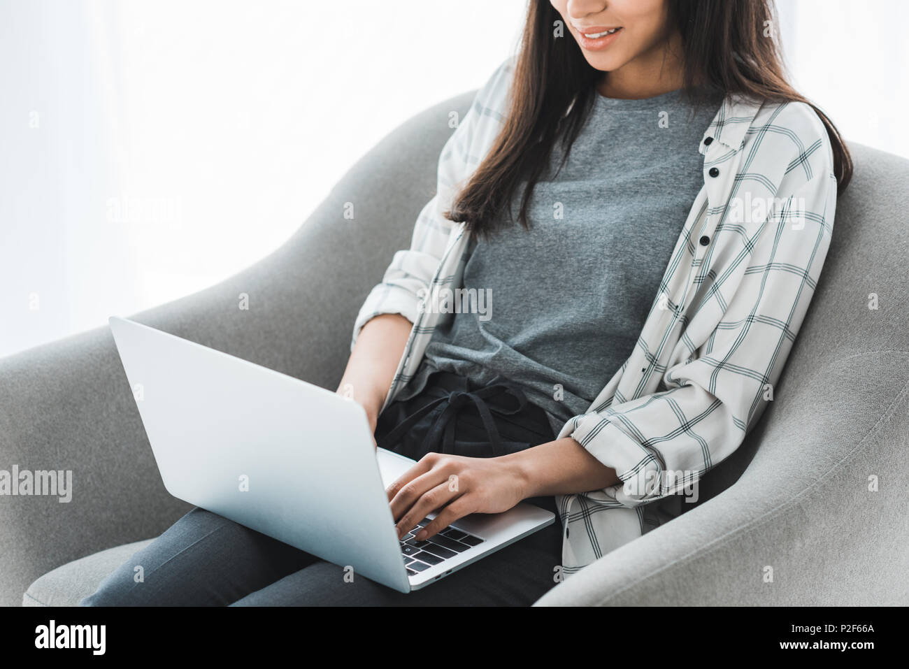 Young girl sitting in chair and working on laptop Stock Photo - Alamy
