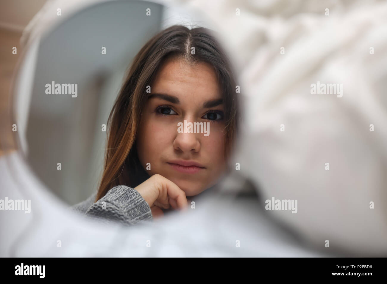 young beautiful girl looking in the mirror, a reflection of the ...