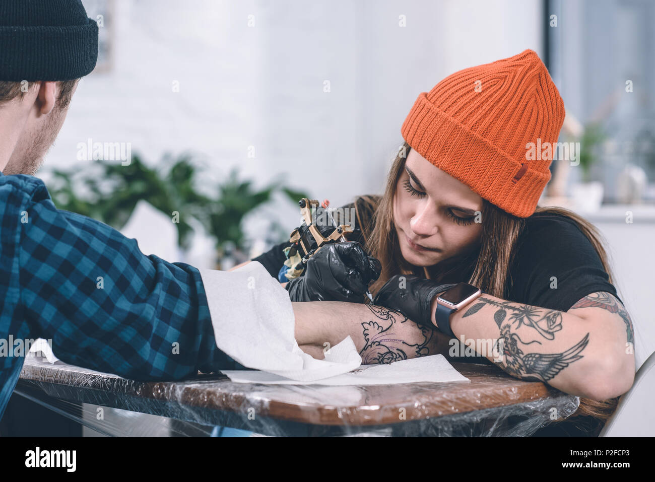 Young man and female tattoo master during tattooing process in studio ...