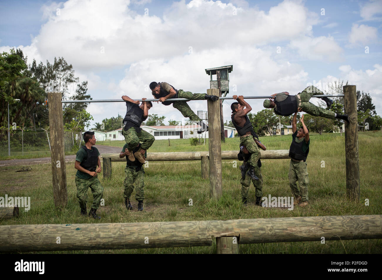 Soldiers with the Belize Defence Force help each other climb a high bar ...