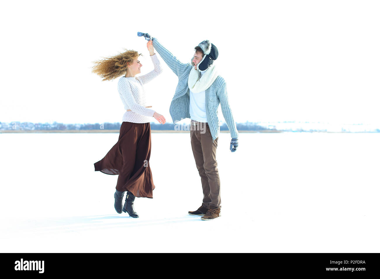 Woman wearing brown skirt and sweater dancing with man in snow ...