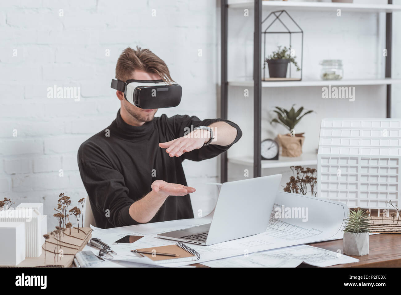 architect in vr headset at workplace with laptop, schemes and building ...
