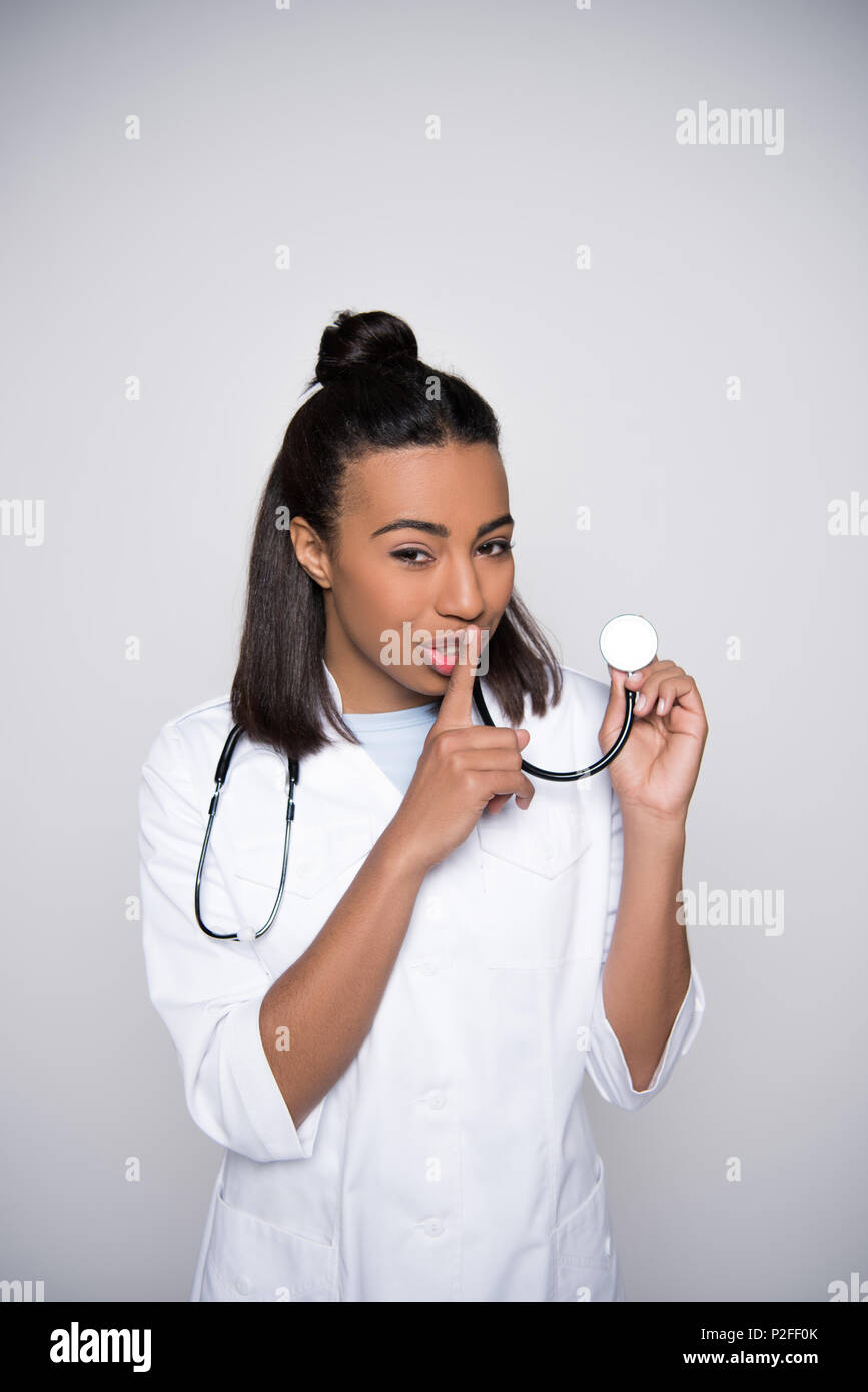 Half-length shot of young female doctor in a white robe posing with ...