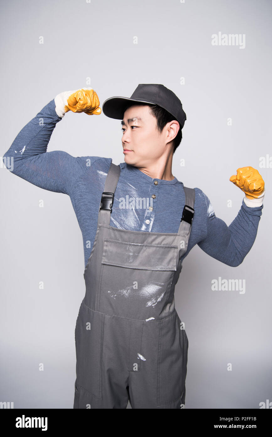 Half-length shot of young construction worker in overalls and safety ...