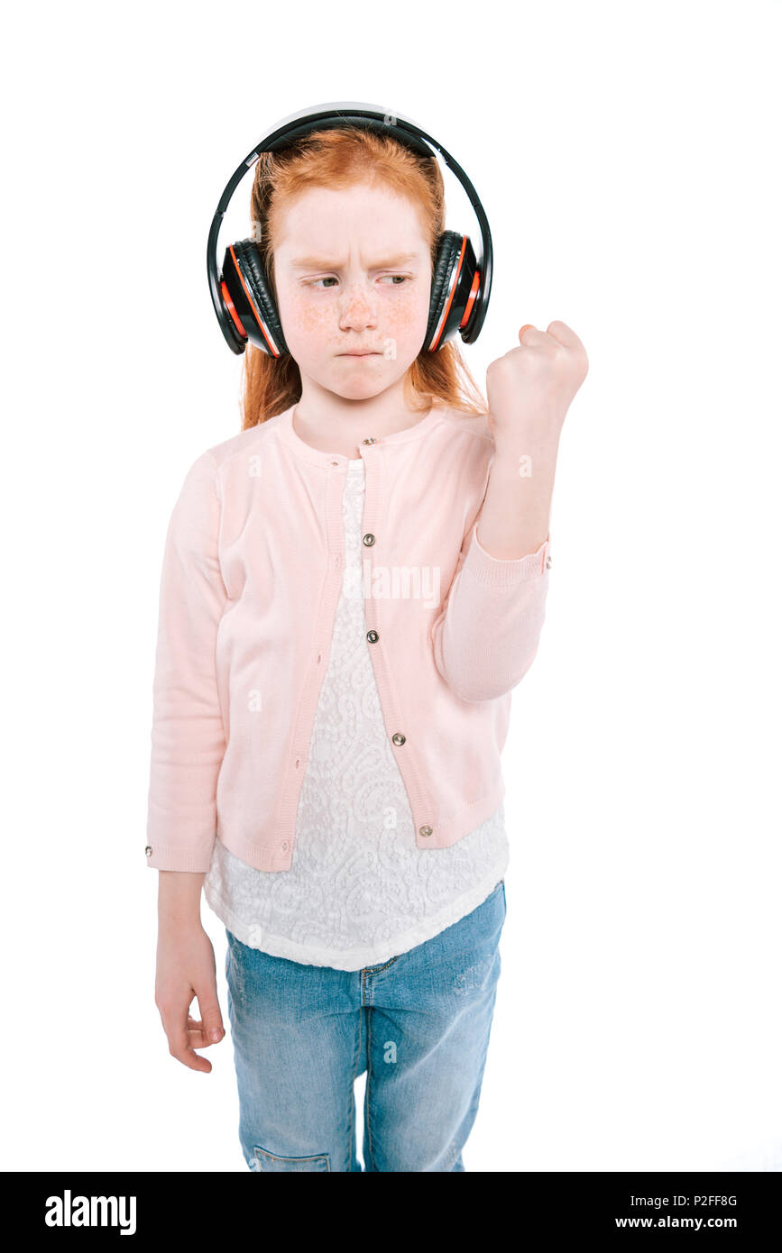 angry female child showing fist and listening music with headphones ...