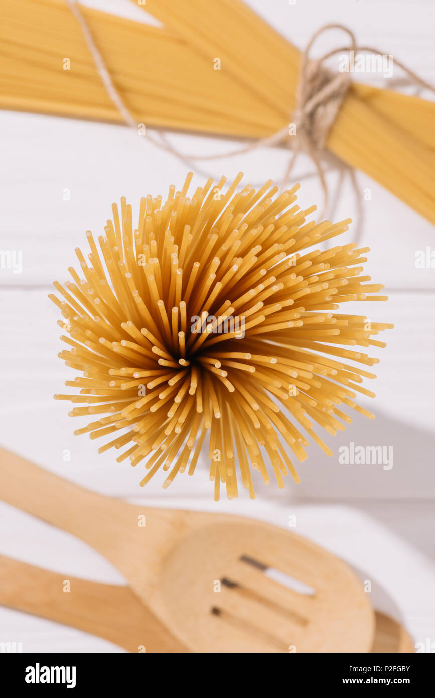 top view of bunch of raw spaghetti on white wooden tabletop with ...