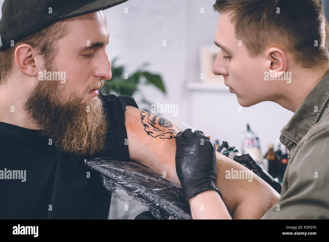 Bearded man and tattoo master during tattoo process in studio Stock ...