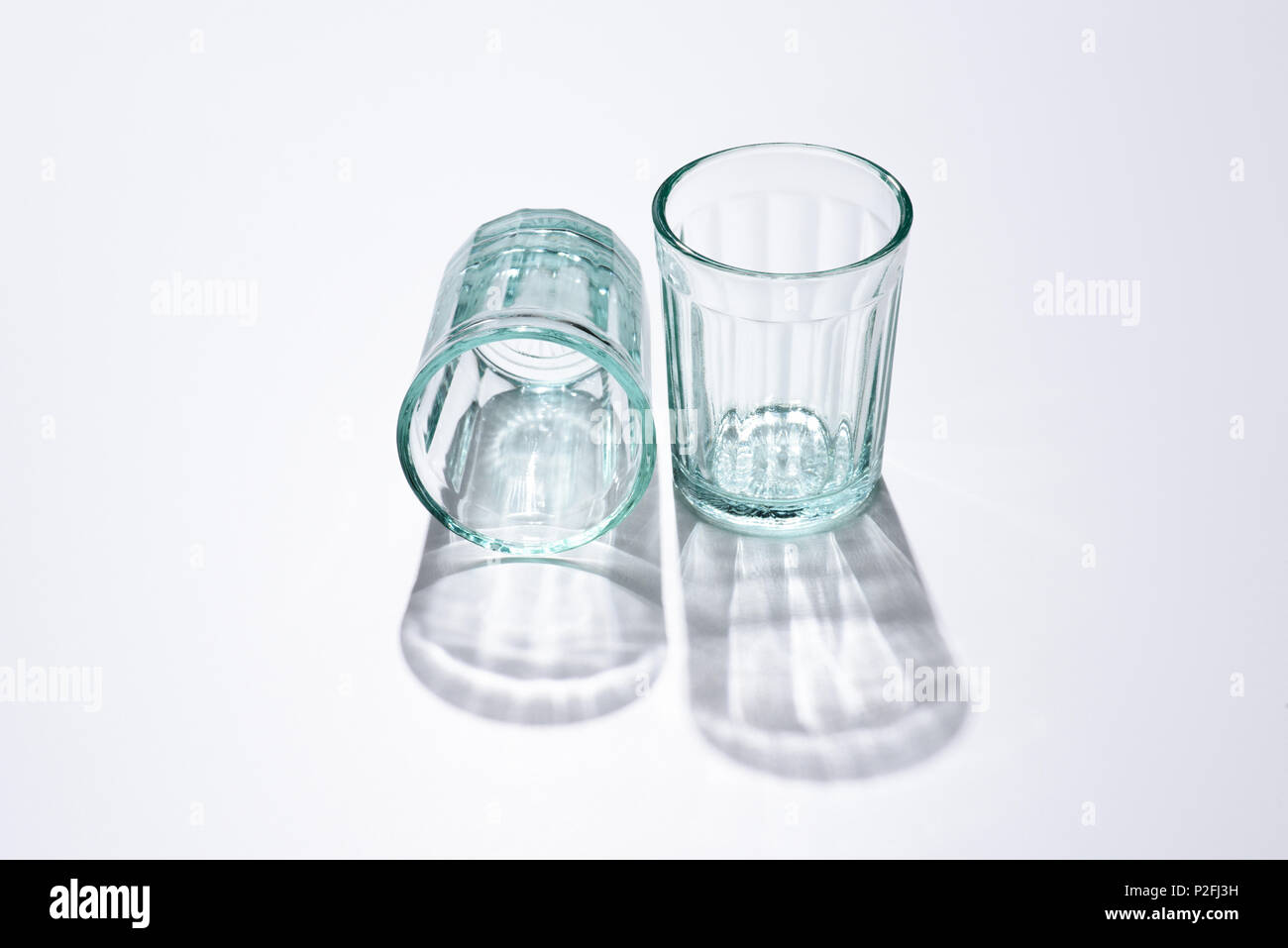 close up view of empty glasses and shadows on white surface Stock Photo ...