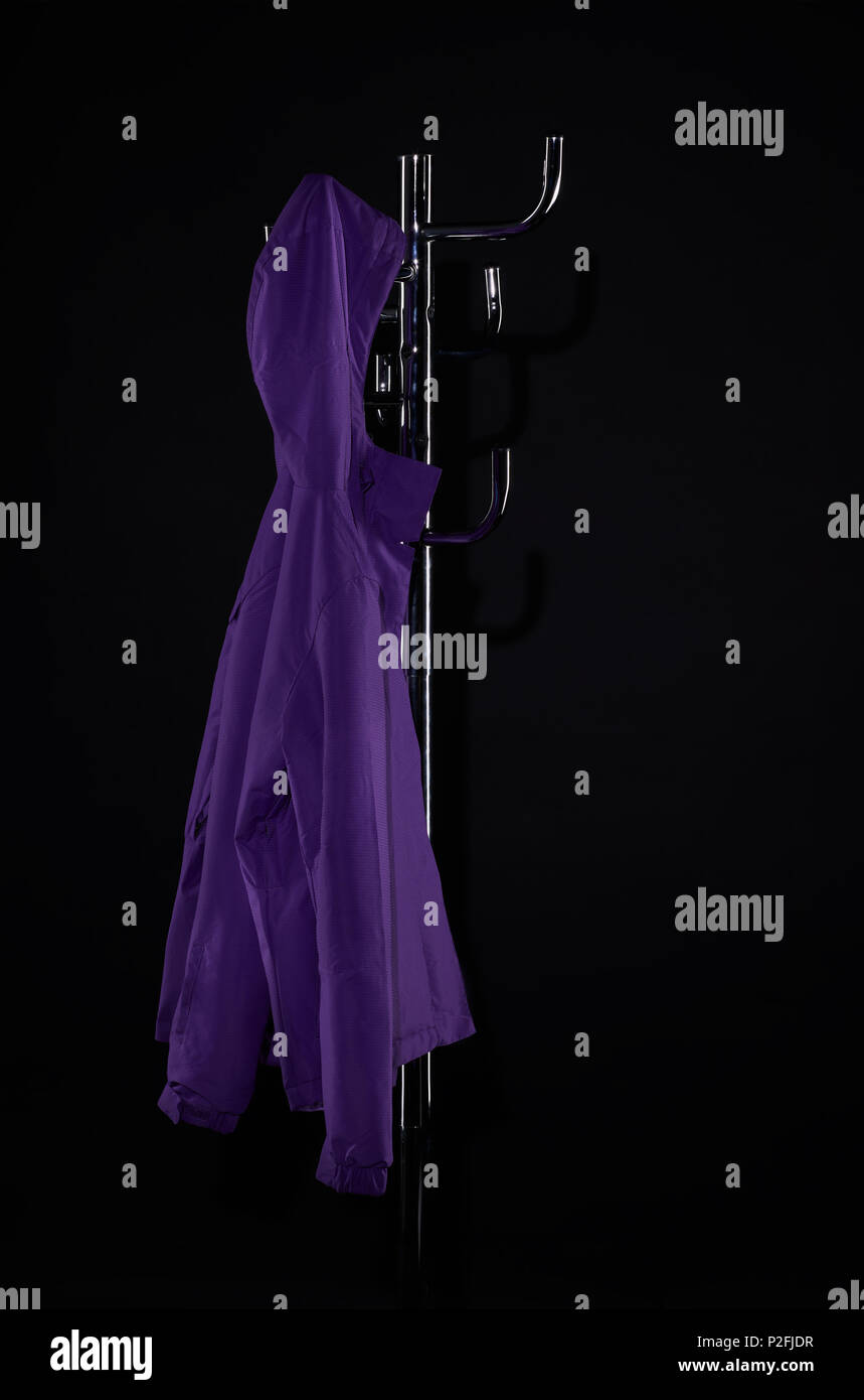 purple raincoat hanging on coat rack isolated on black Stock Photo - Alamy