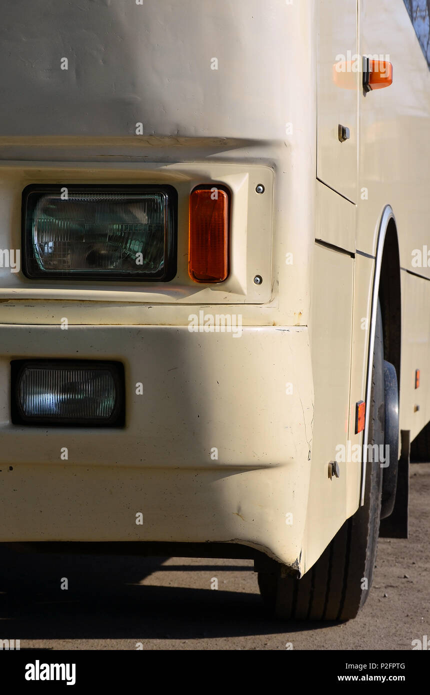 Photo of the hull of a large and long yellow bus. Close-up front view ...