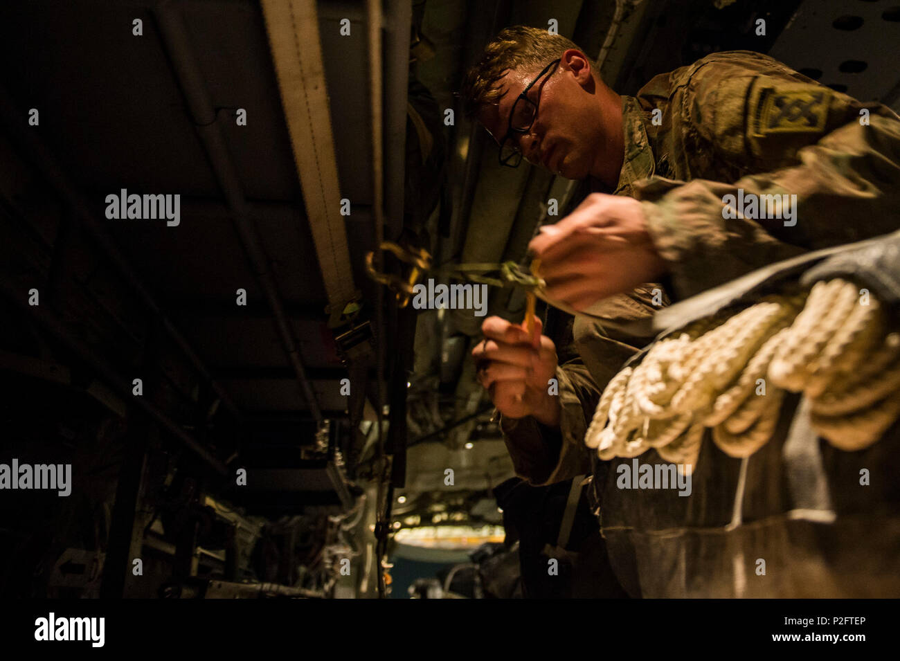 A U.S. Army parachute rigger ties down a chute line on a pallet of ...
