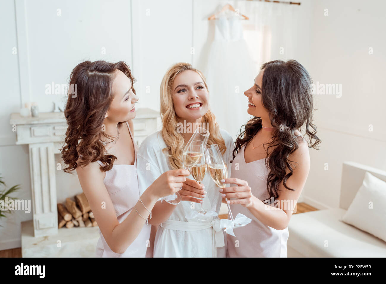 beautiful young bride with bridesmaids toasting with champagne glasses ...