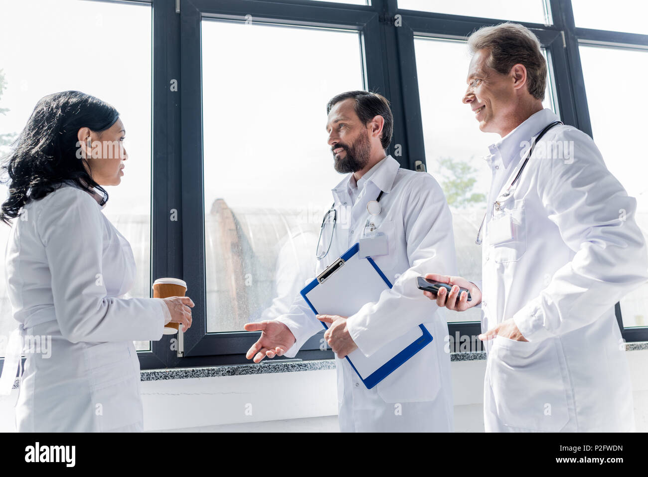 group of professional doctors talking and drinking coffee in hospital ...