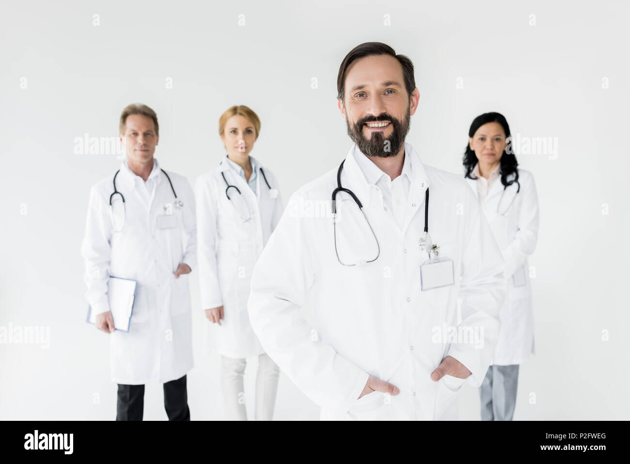 handsome bearded doctor smiling at camera while professional colleagues ...