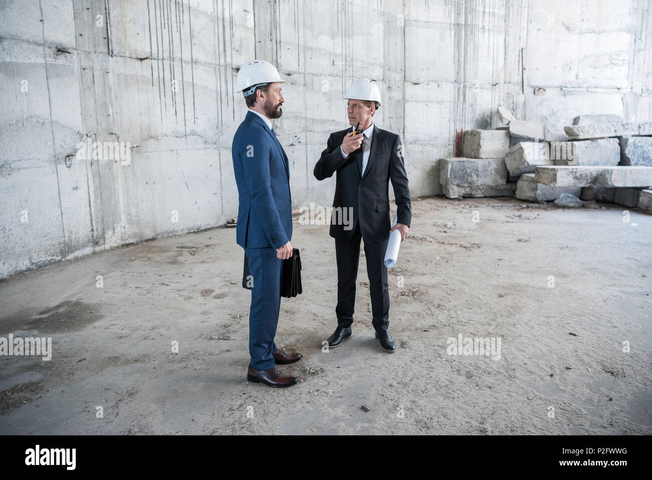 Two professional mature architects with blueprint working at ... Two professional mature architects with blueprint working at ...