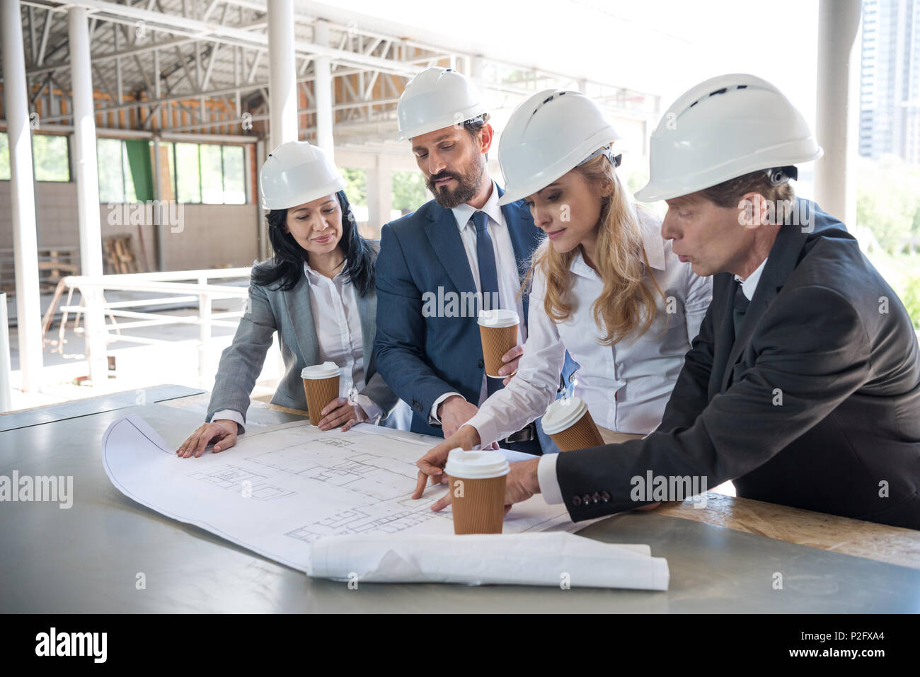 group of contractors in formal wear working with blueprints at ...
