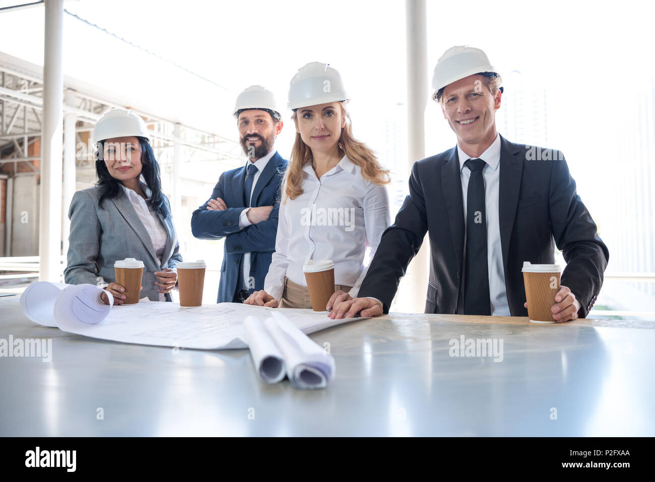 team of multiethnic contractors in formal wear working with blueprints ...