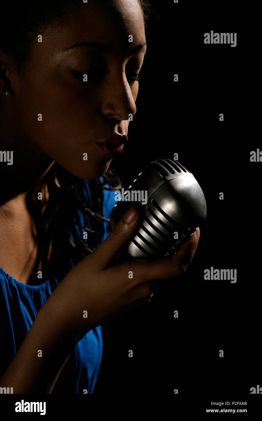 Young woman singing into a 50s style microphone Stock Photo - Alamy