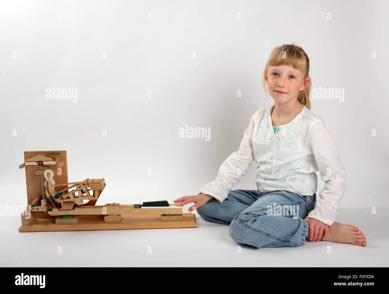 child pressing down the key of a model of a grand piano action Stock ...