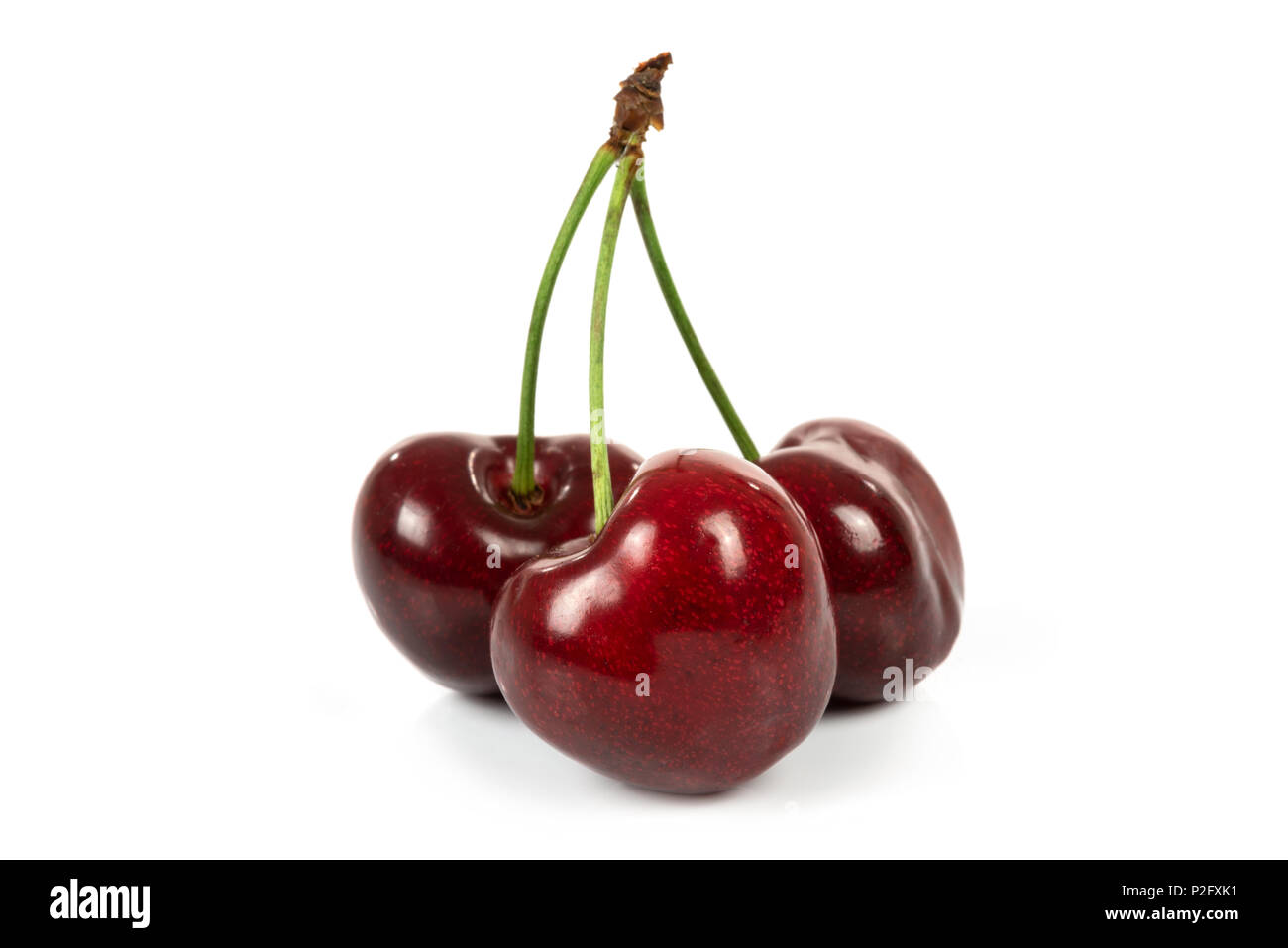 Three ripe perfect cherries isolated on a white background in close-up ...
